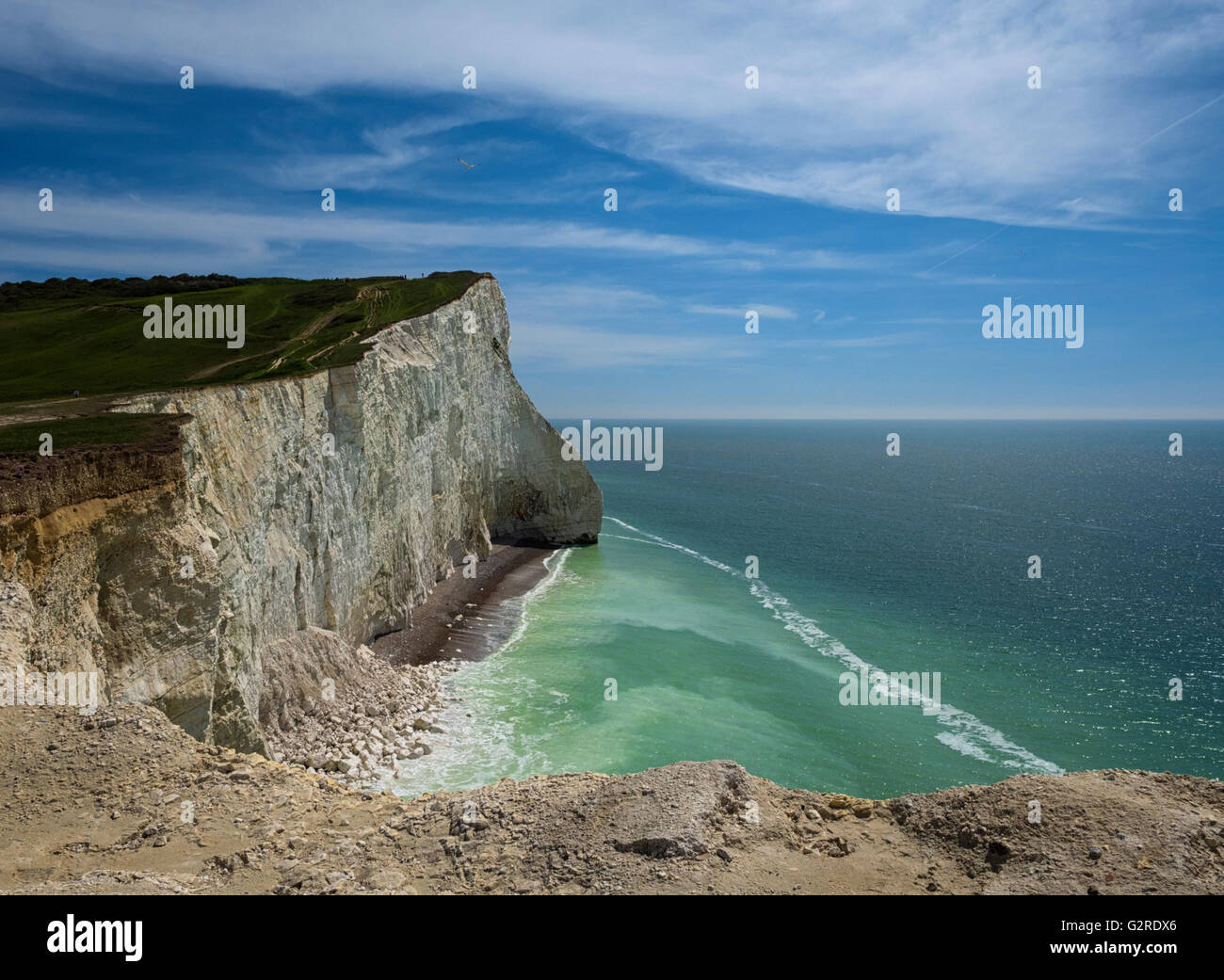 Crumbling chalk cliffs of the Sussex Downs tower above the beach at ...