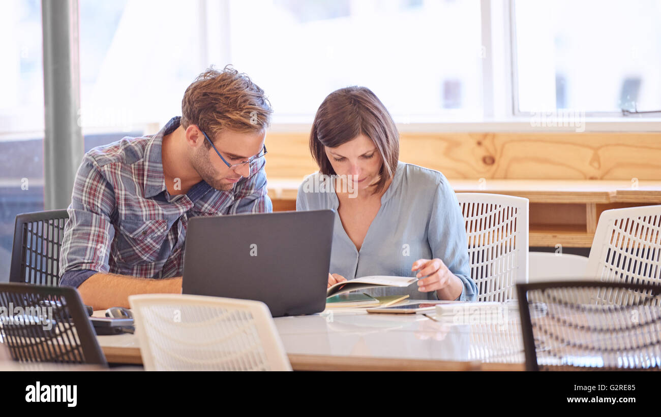 Male and female business partners working together at conference table ...