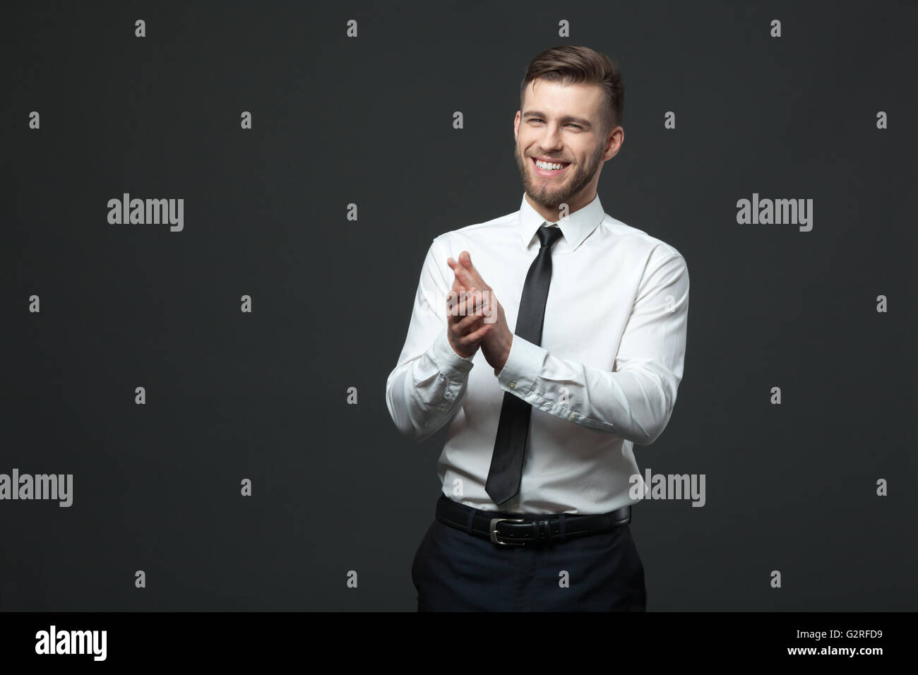Studio portrait of young happy handsome businessman clapping hands ...