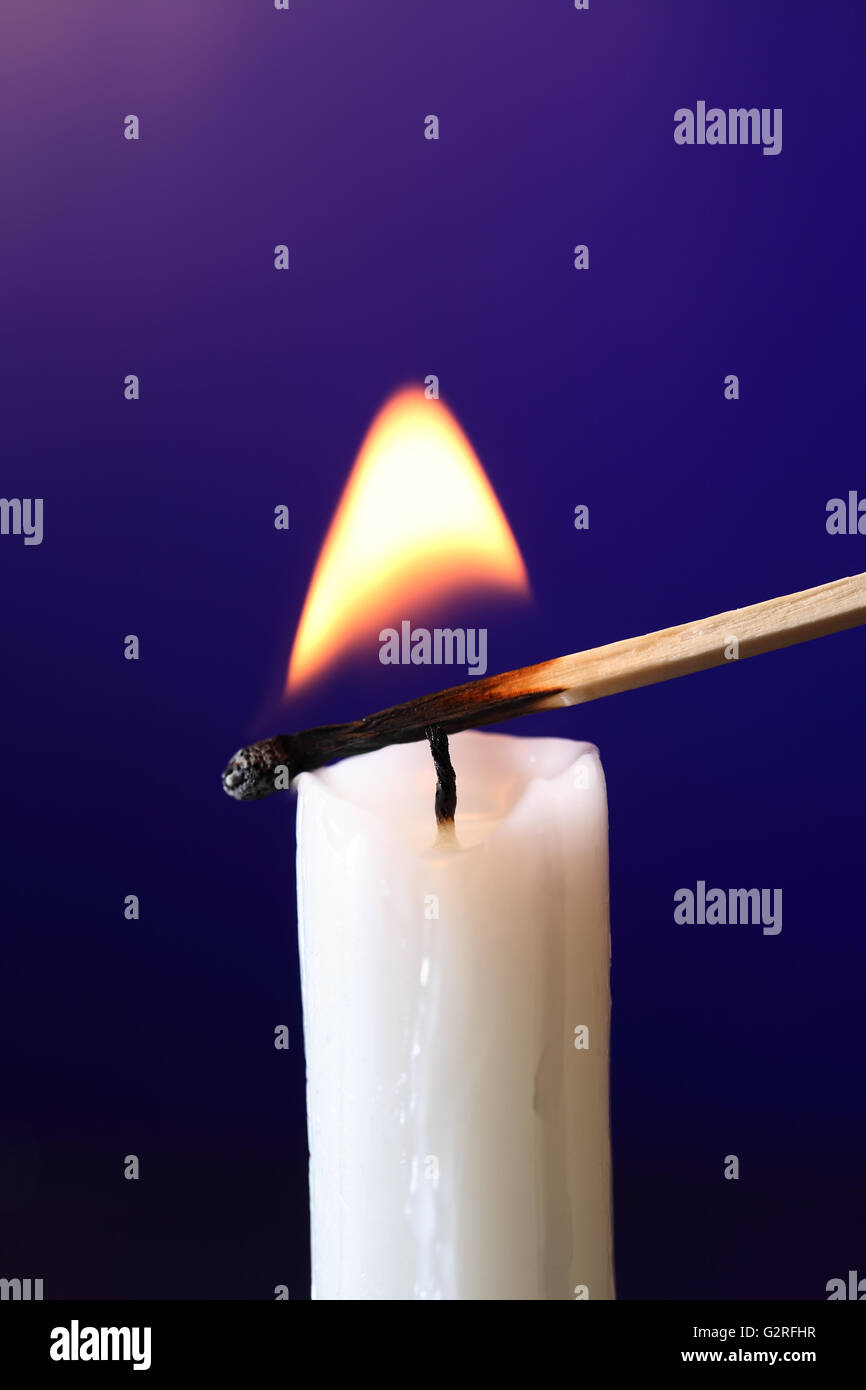 Closeup of candle inflamed with match on dark background Stock Photo ...
