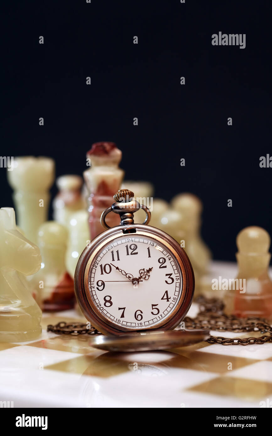 Vintage pocket watch on chessboard against dark background Stock Photo ...