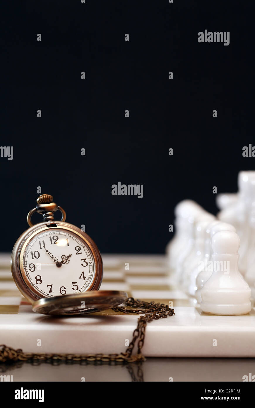 Vintage pocket watch on chessboard against dark background Stock Photo ...