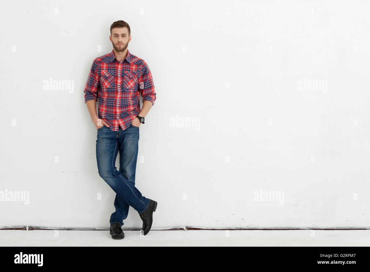 Portrait of handsome young guy standing against white wall Stock Photo ...