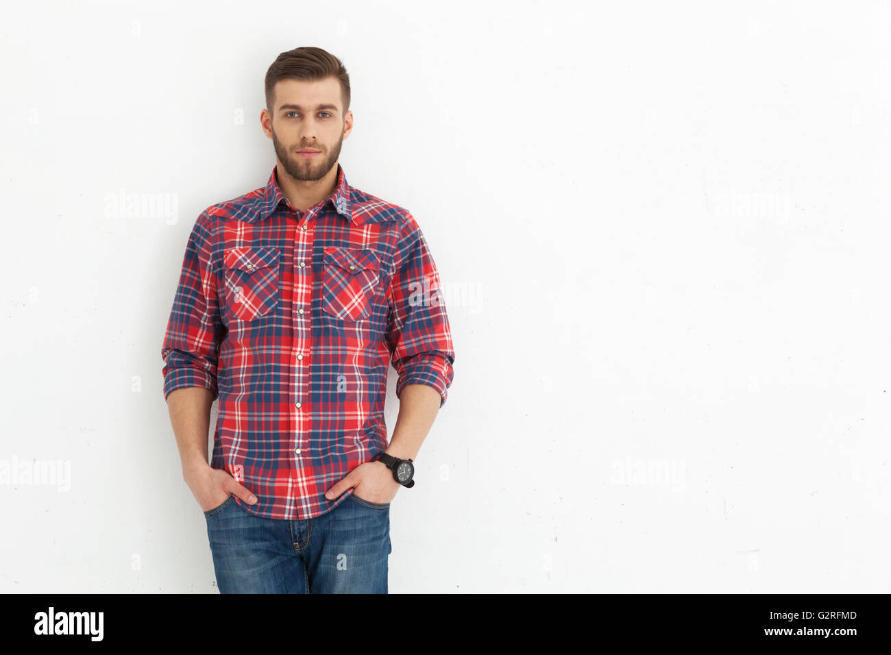 Portrait of handsome young guy standing against white wall Stock Photo ...