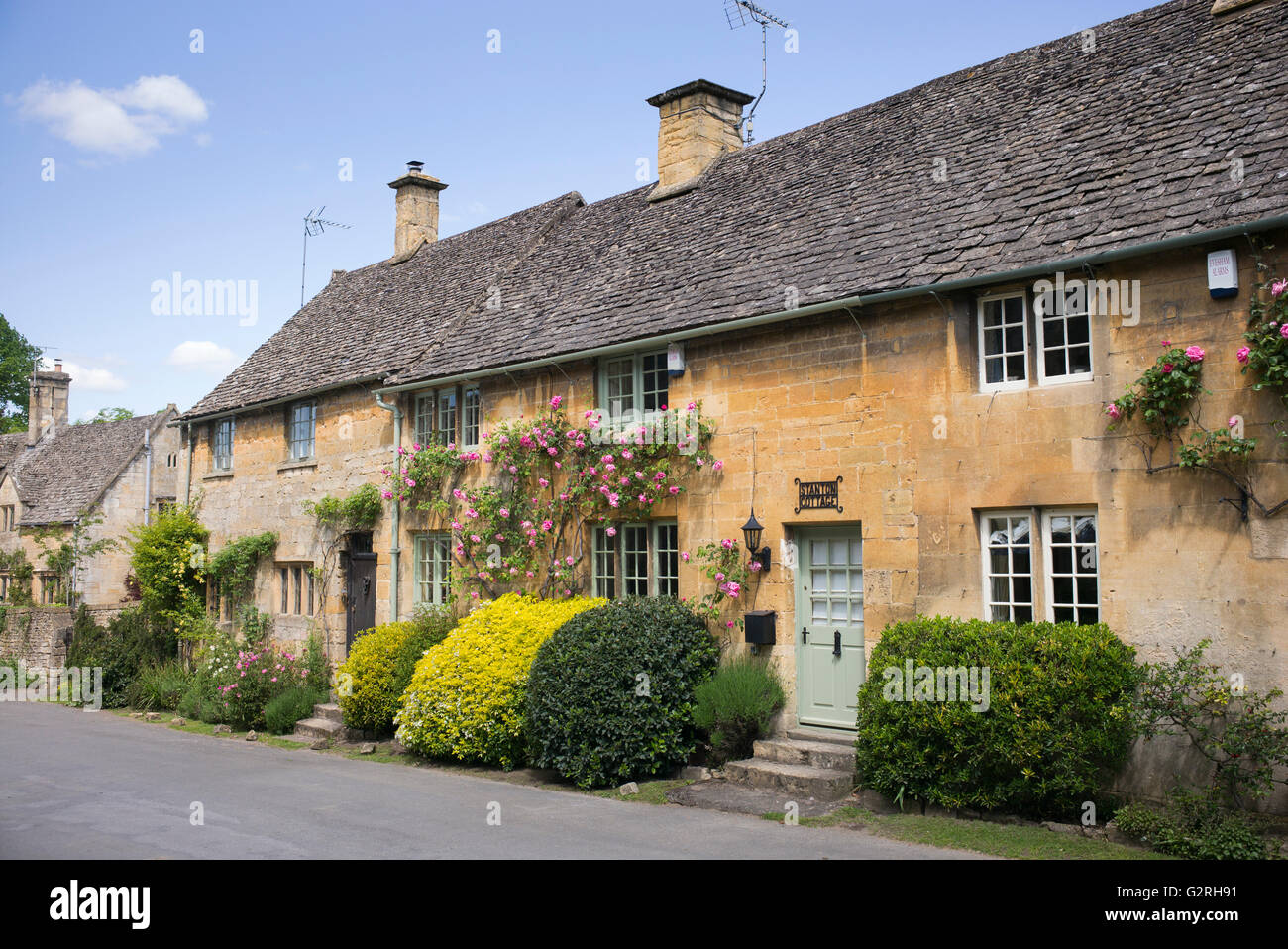 Cotswold stone cottage window surrounded with pink roses. Stanton ...