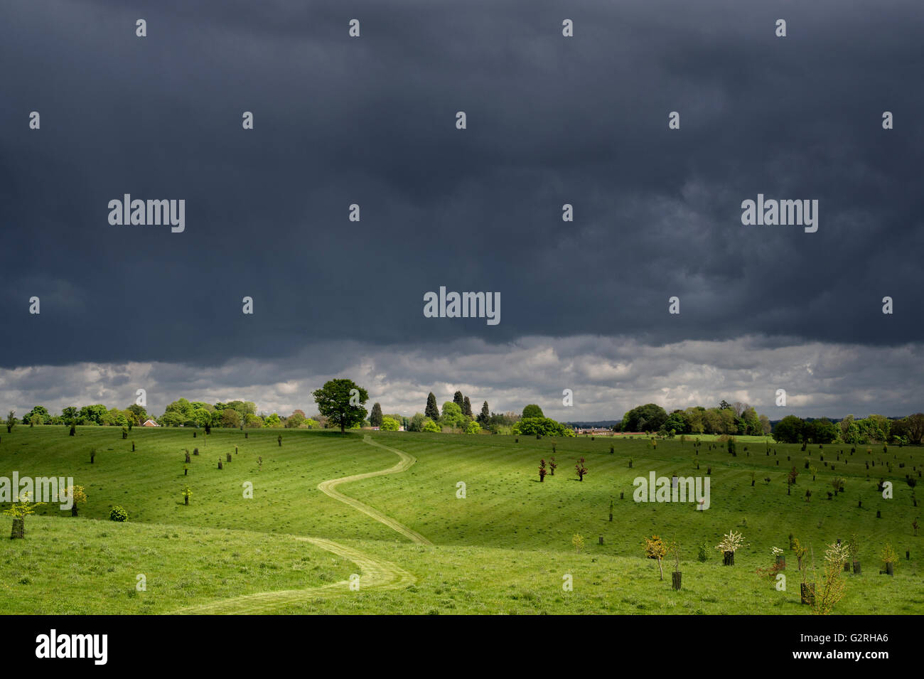 Footpath lit up against a dark stormy sky through an Oxfordshire field ...