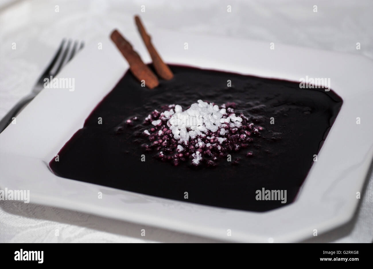 A white square bowl of acai served with tapioca and garnished with ...