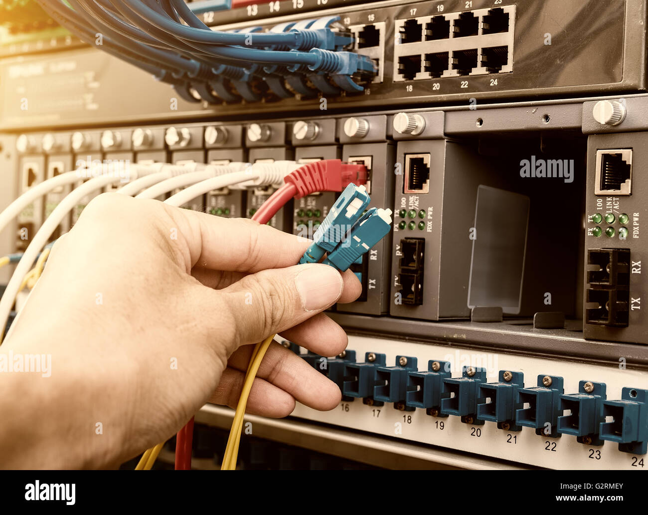 man working in network server room with fiber optic hub for digital ...