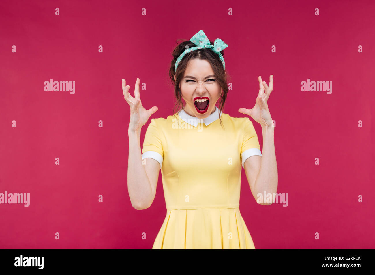 Crazy furious young woman standing and shouting over pink background ...