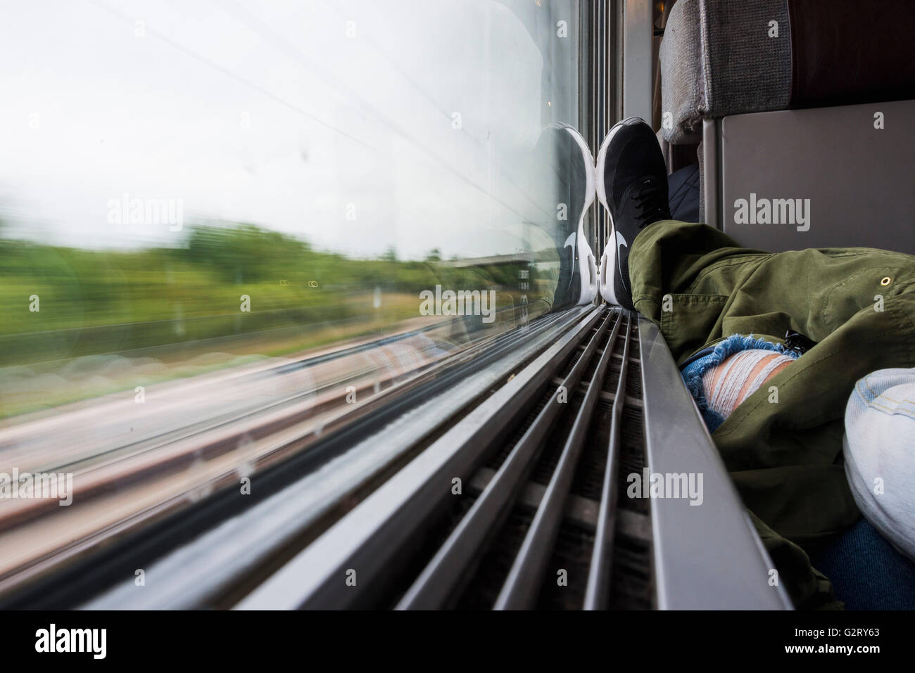 A young woman placing her feet on a window frame inside a train Stock ...