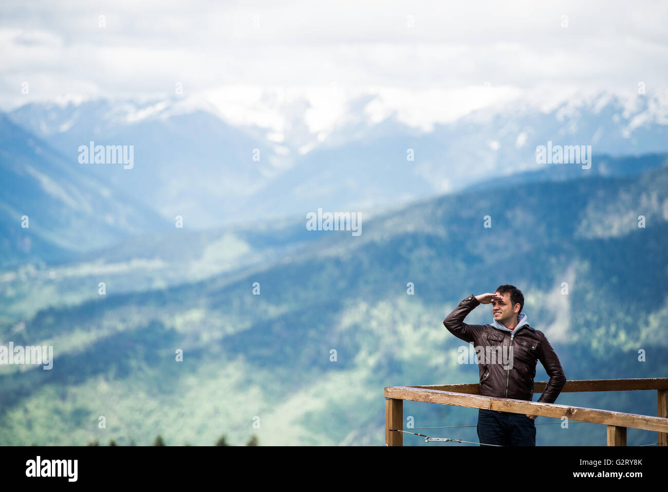 Young man in the mountains looking with hand over his eyes Stock Photo ...