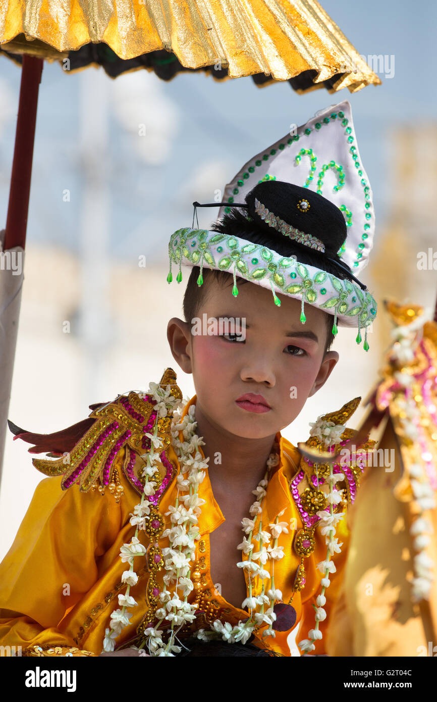 A boy dressed for shinbyu novitiation ceremony carried on shoulders ...
