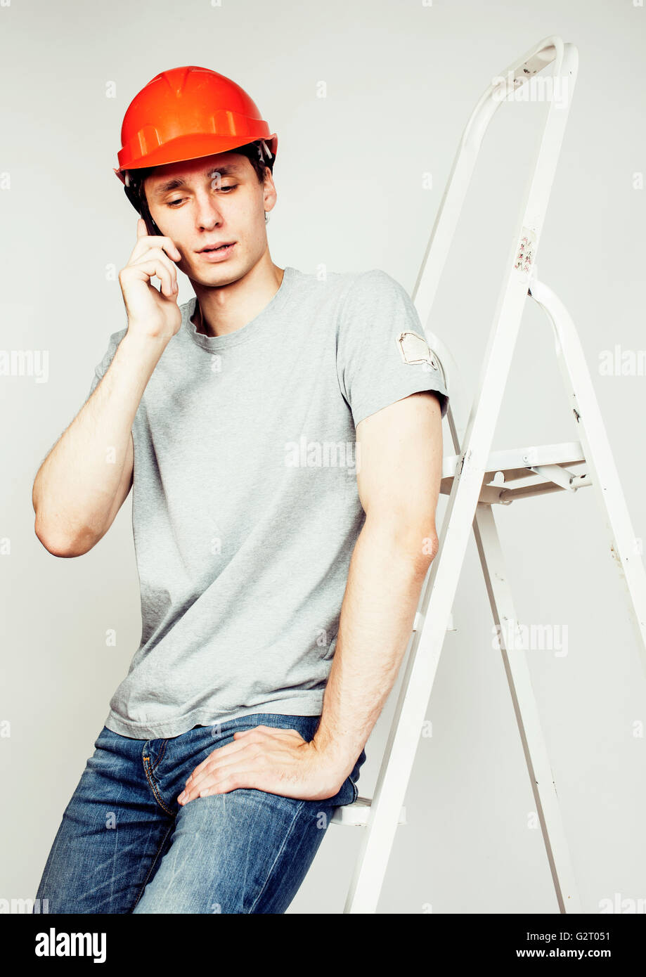 young real hard worker man isolated on white background on ladder ...