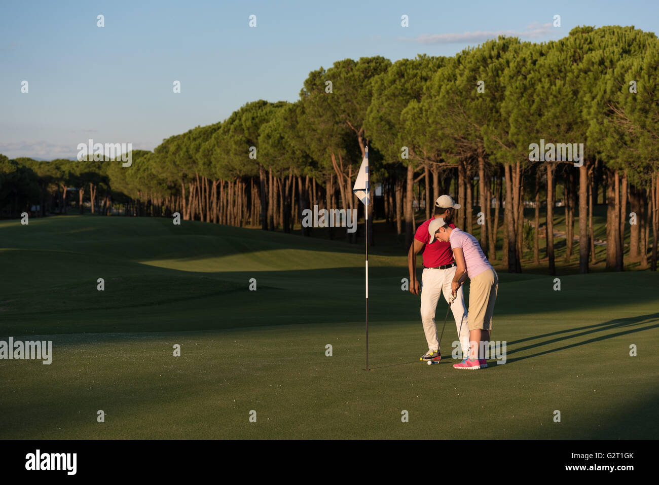 male golf instructor teaching female golf player, personal trainer ...