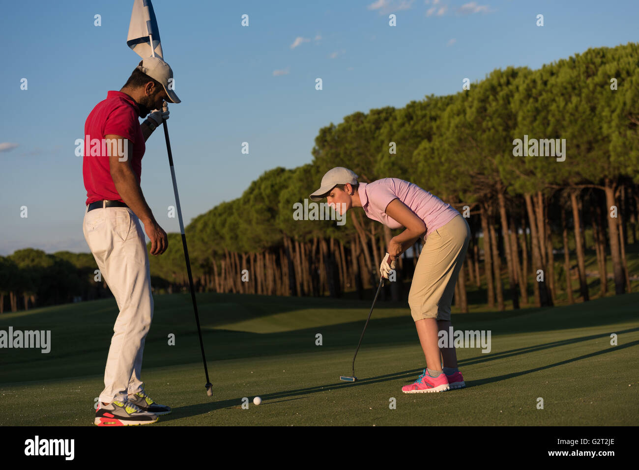 male golf instructor teaching female golf player, personal trainer ...