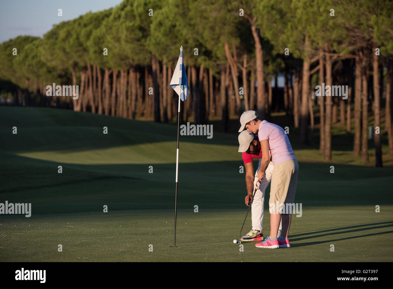 male golf instructor teaching female golf player, personal trainer ...