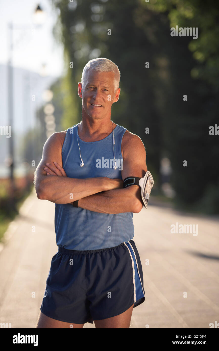 portrait of handsome senior jogging man while relaxing and take break ...