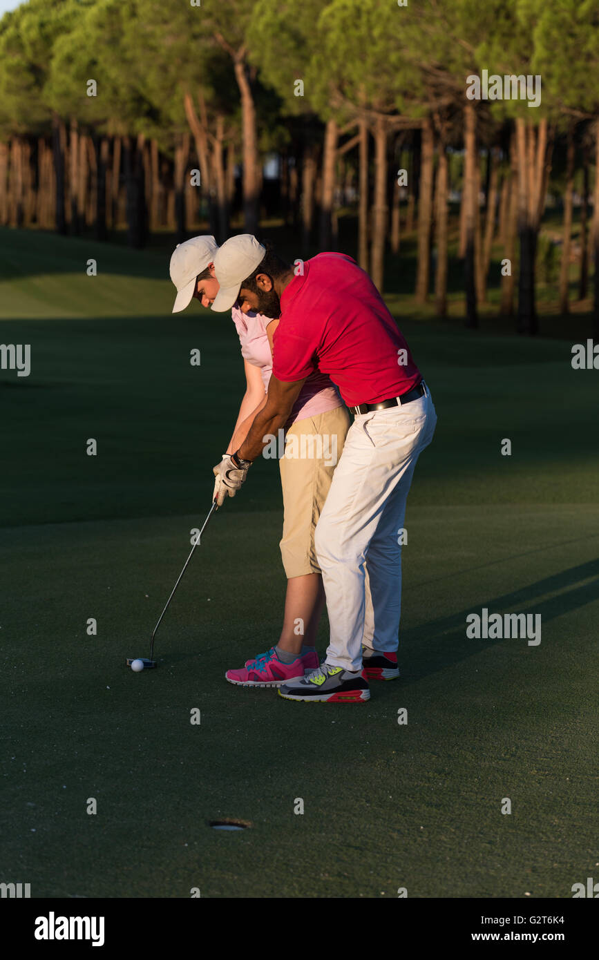 male golf instructor teaching female golf player, personal trainer ...