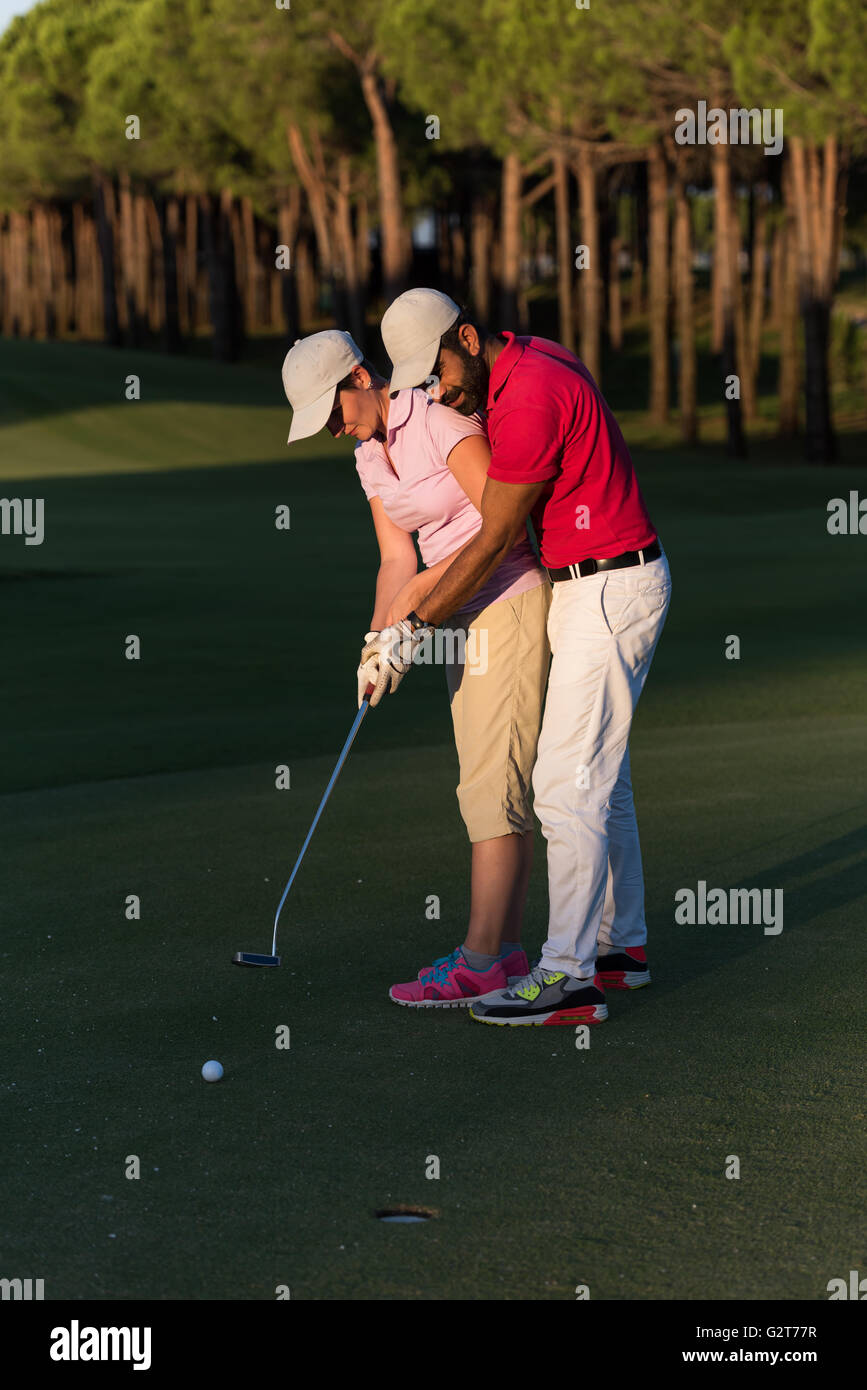 male golf instructor teaching female golf player, personal trainer ...