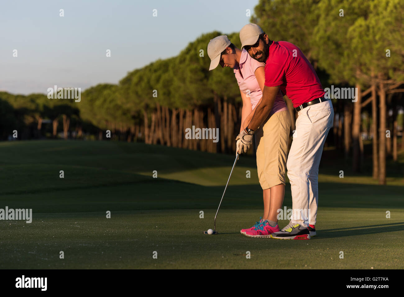 male golf instructor teaching female golf player, personal trainer ...
