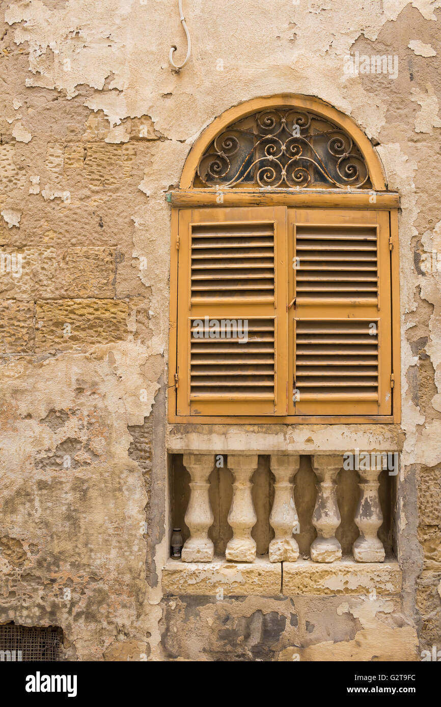 Facade of an old stone house. Window with an arch and yellow closed ...