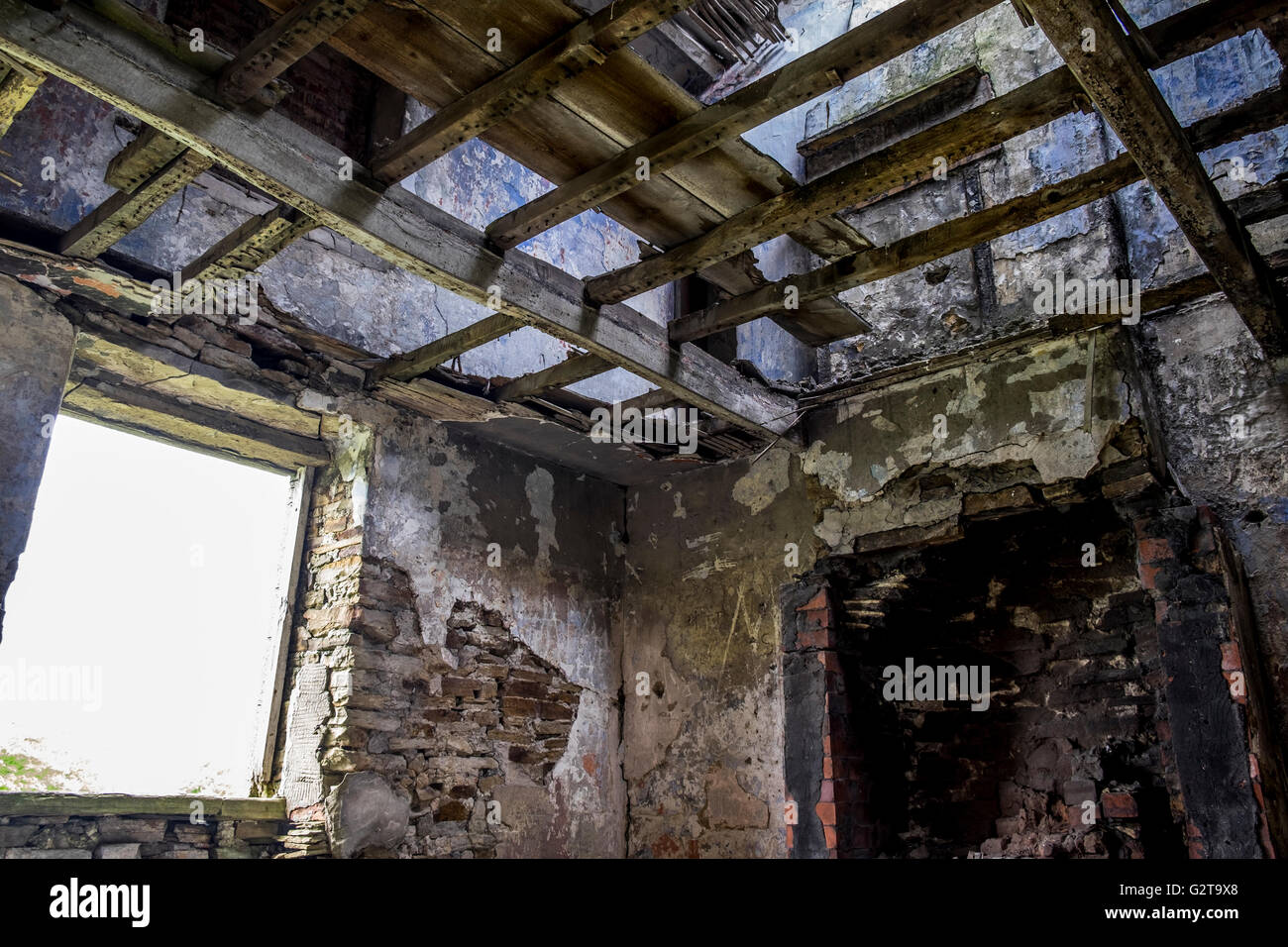 A derelict house with the upper floor and roof missing and plaster ...