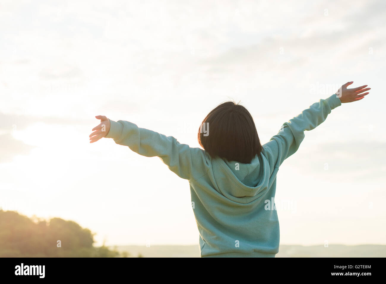 Pretty happy asian woman stretching on the blue sky background. Moment ...