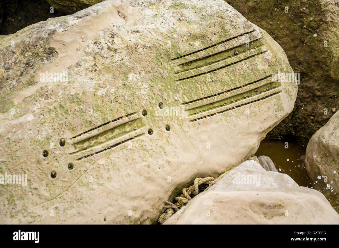 Lines and rocks engraved into a rock which is part of a sea defense ...