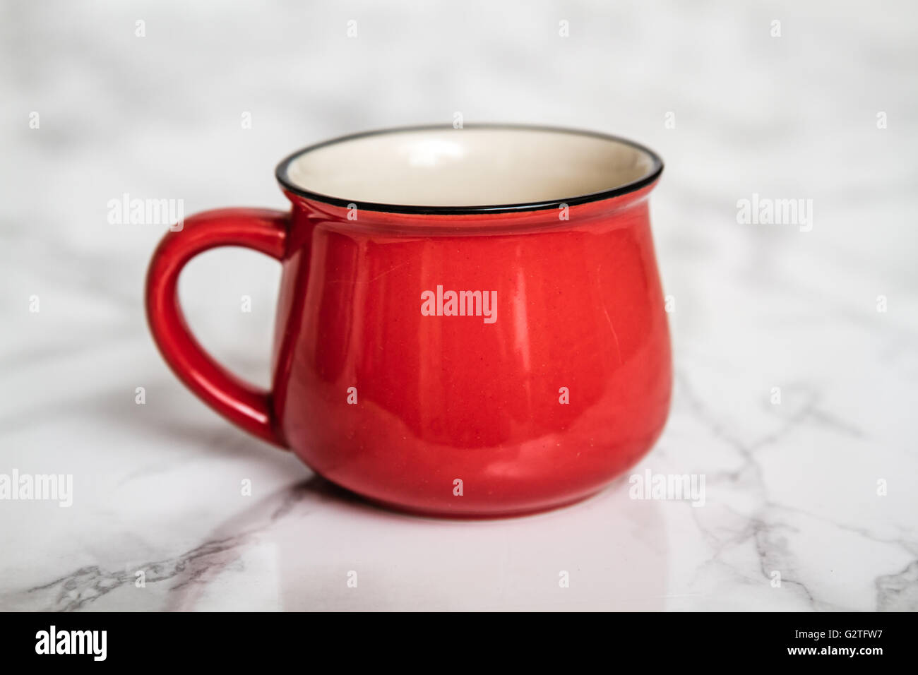 Red ceramic mug with enamel look on white marble background Stock Photo ...