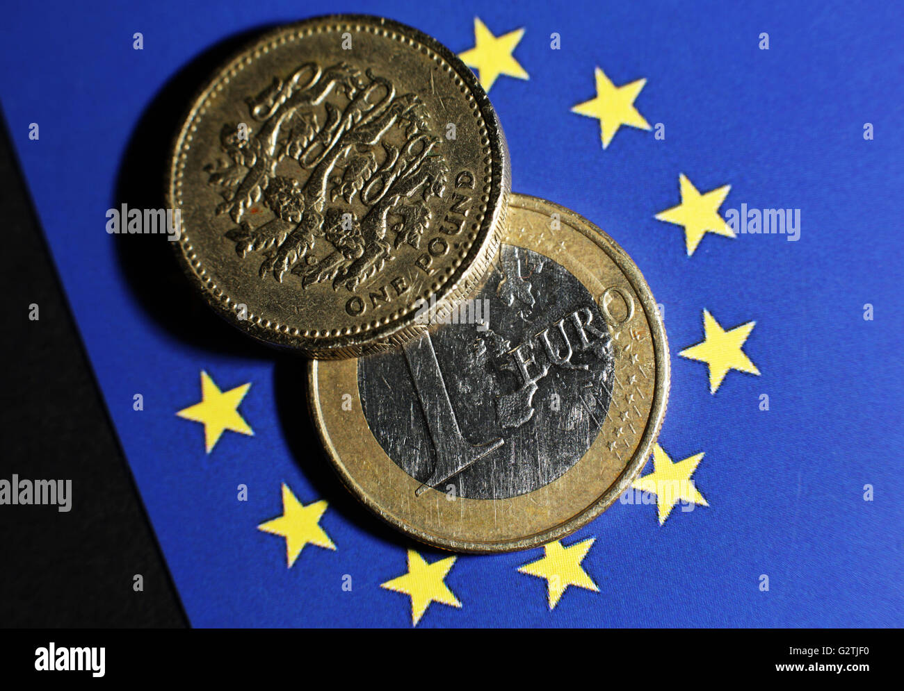 A 1 euro coin and a One Pound coin placed on a backdrop of The European ...