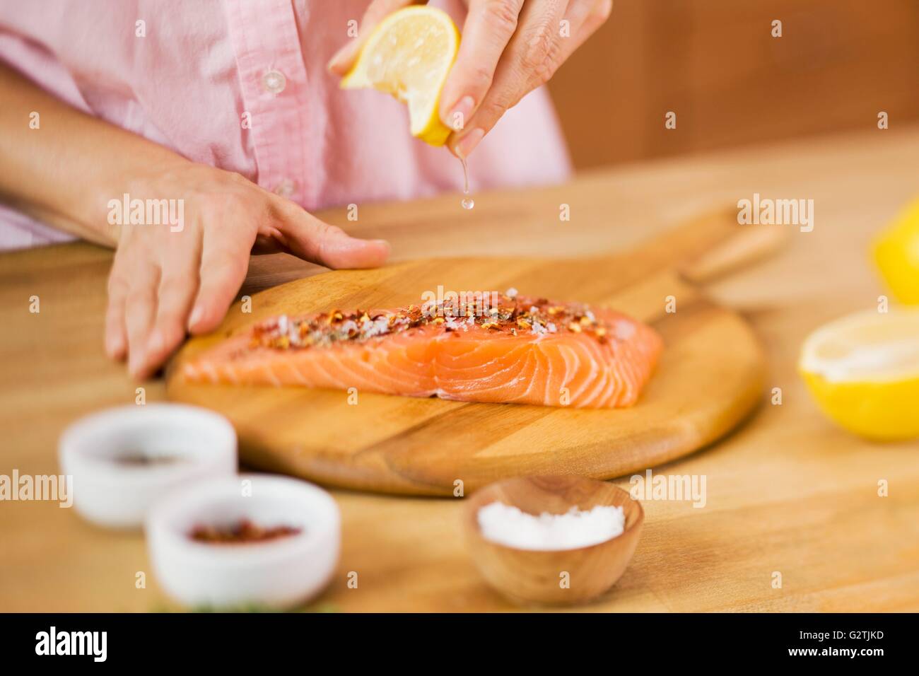Woman Squeezing a Lemon Wedge over Salmon Stock Photo - Alamy