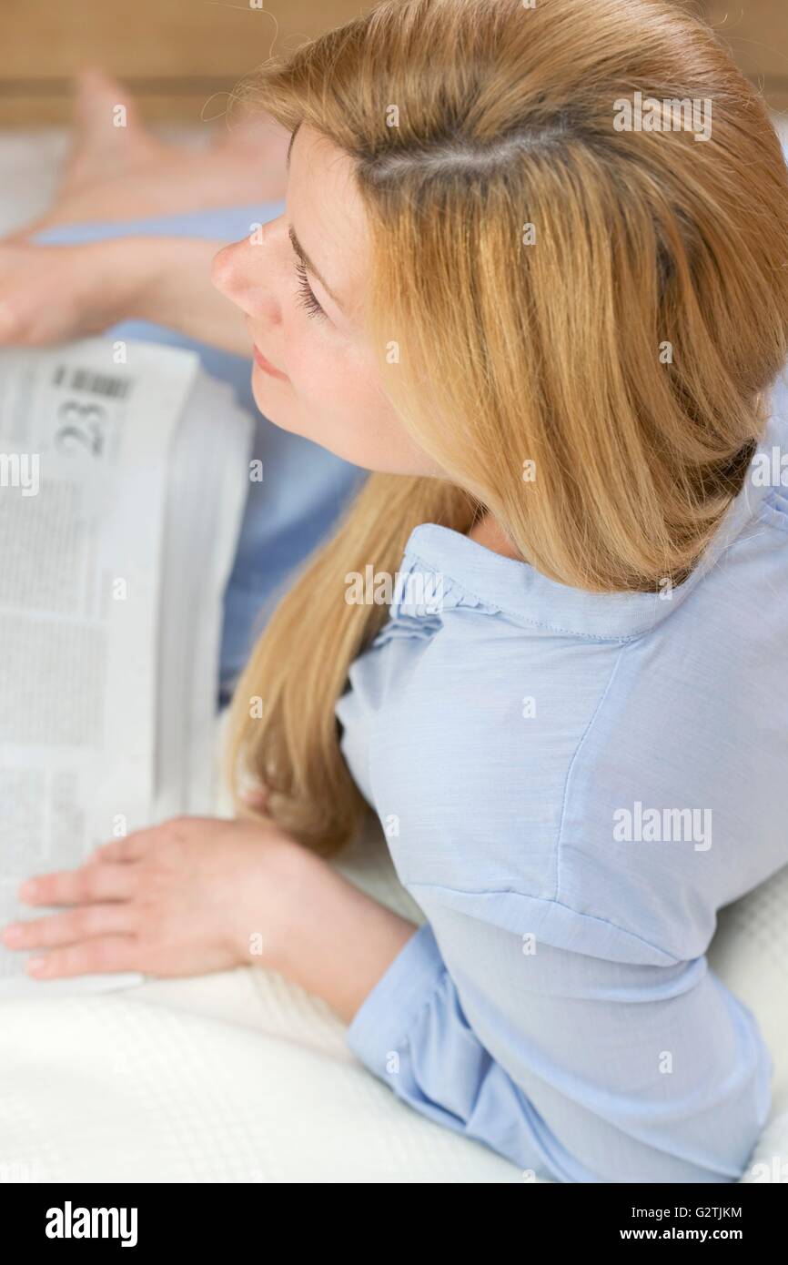 Blond woman reading a newspaper Stock Photo - Alamy