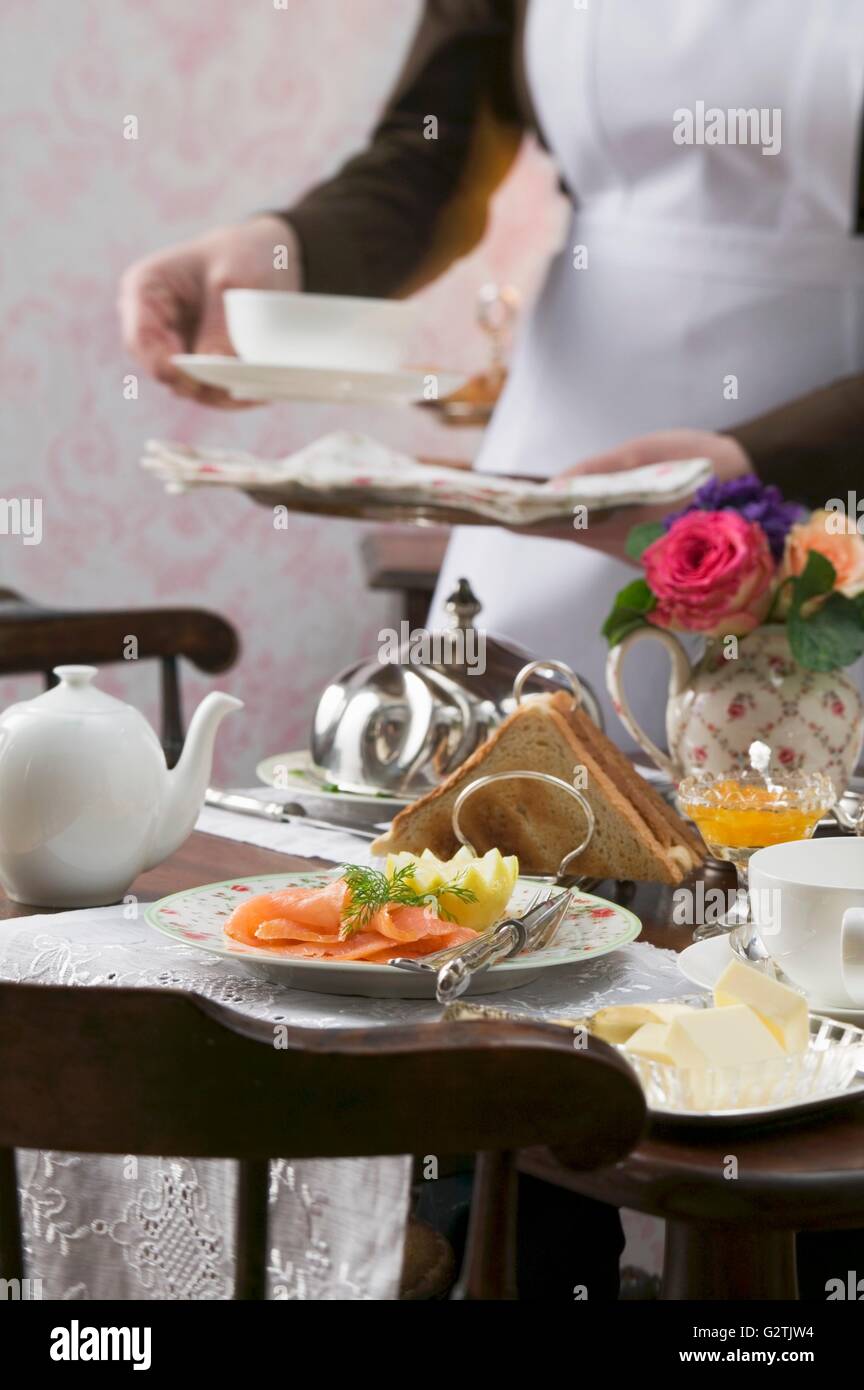 Smoked salmon and toast on table, maid in background Stock Photo - Alamy