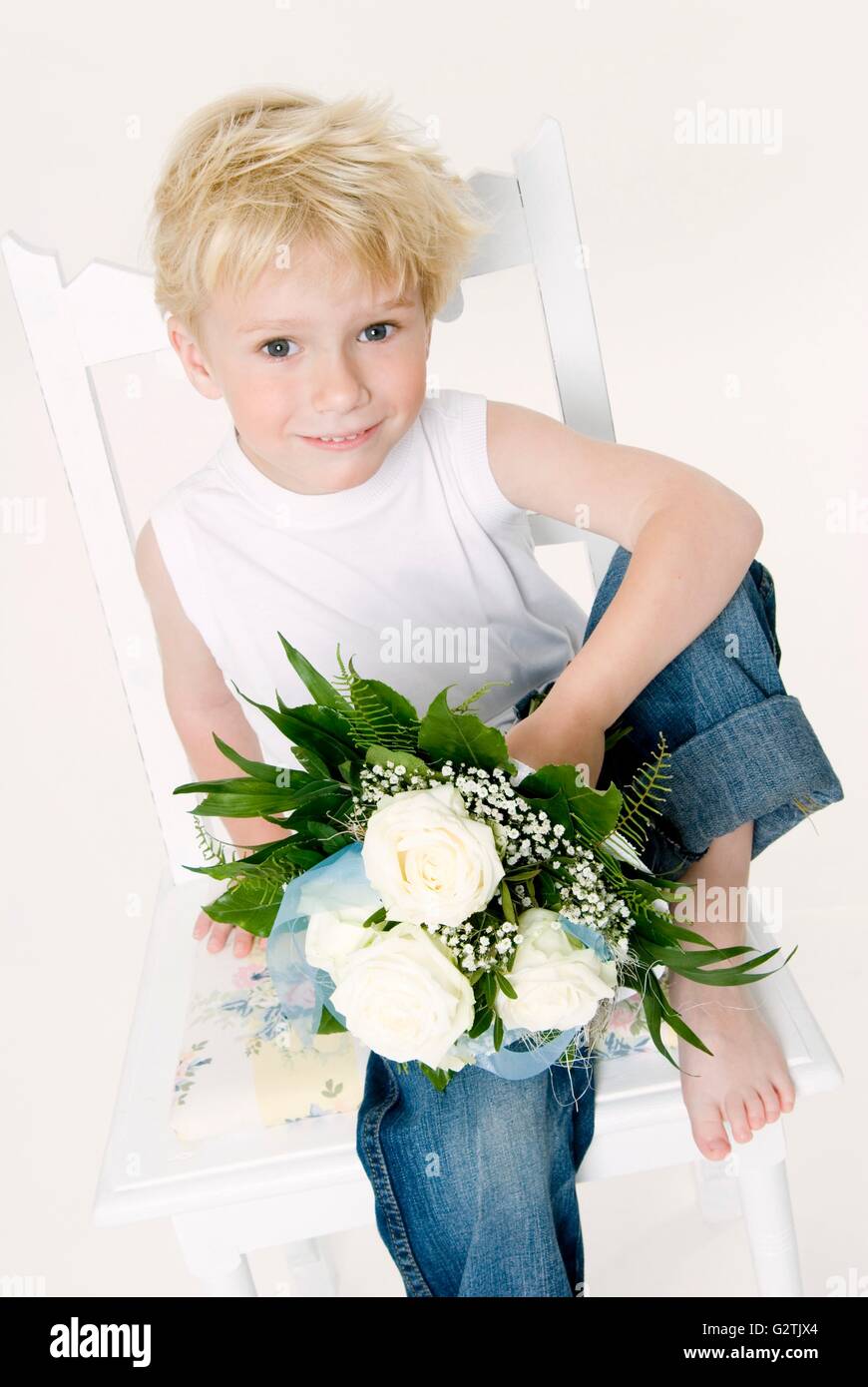 Boy with bouquet of white roses sitting on a chair Stock Photo - Alamy