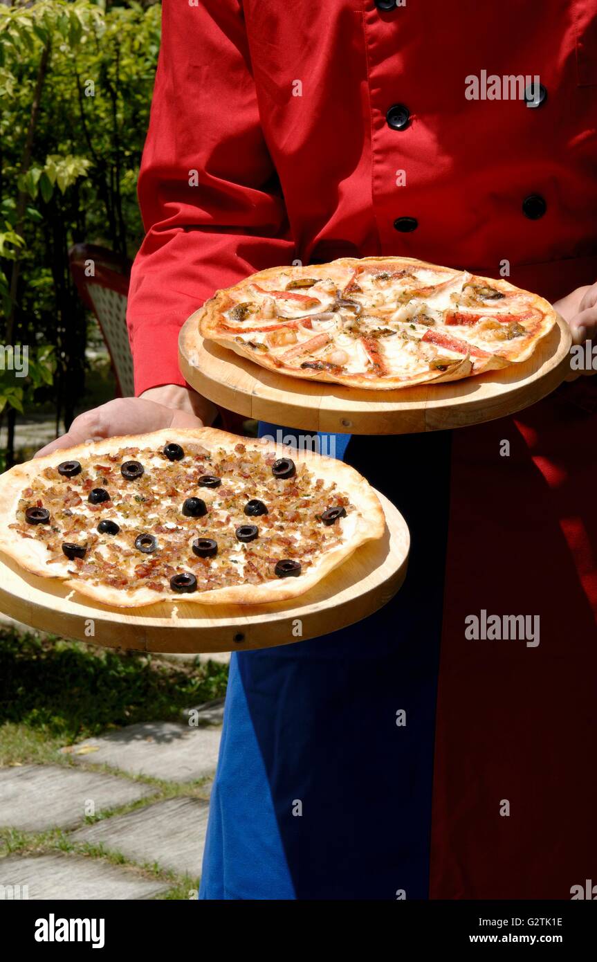 Chef carrying two pizzas on wooden boards Stock Photo - Alamy