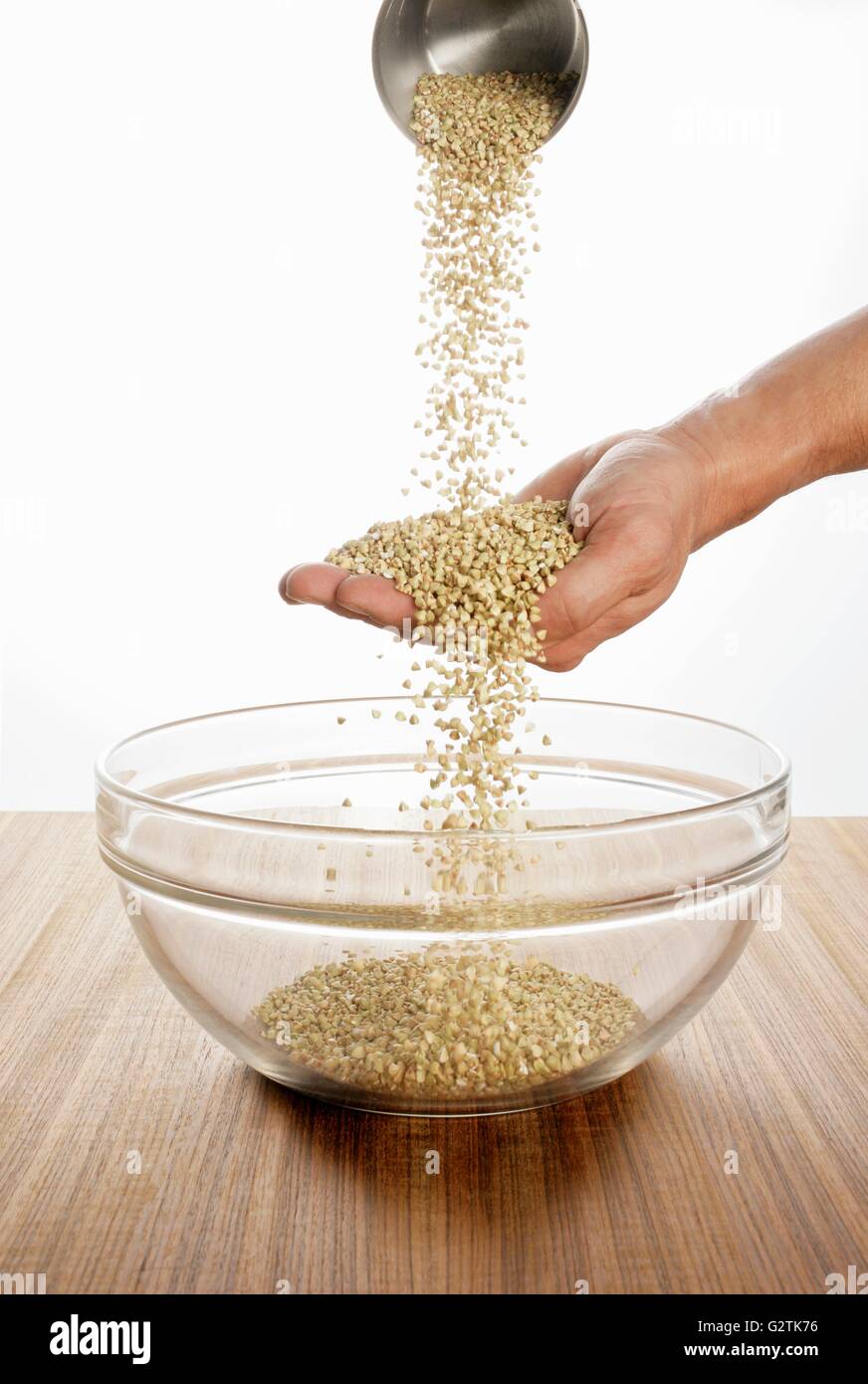 Someone pouring buckwheat over their hand into a glass bowl Stock Photo ...