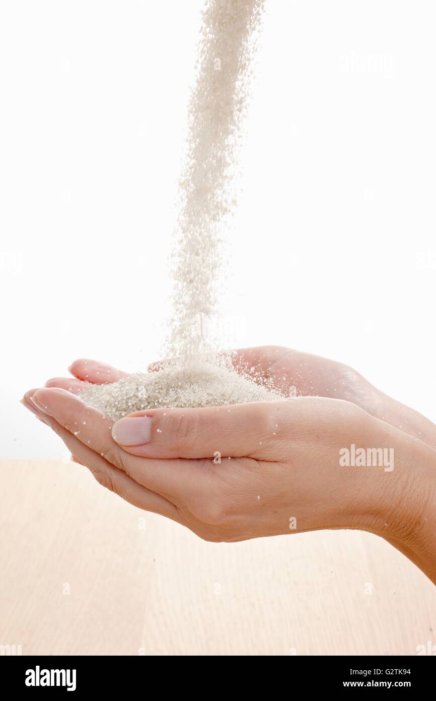 Raw sugar flowing into hands Stock Photo - Alamy