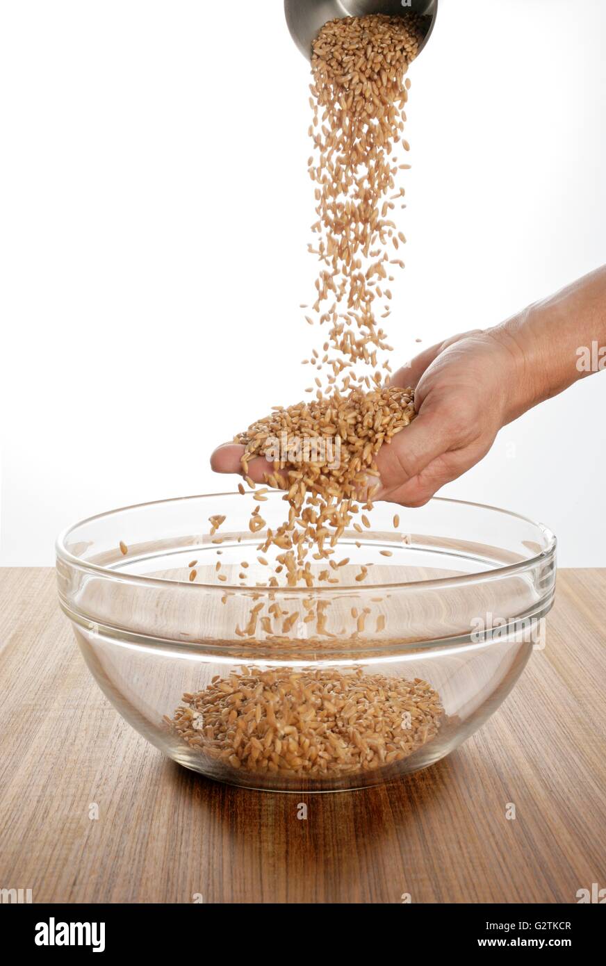 Someone pouring spelt over their hand into a glass bowl Stock Photo - Alamy