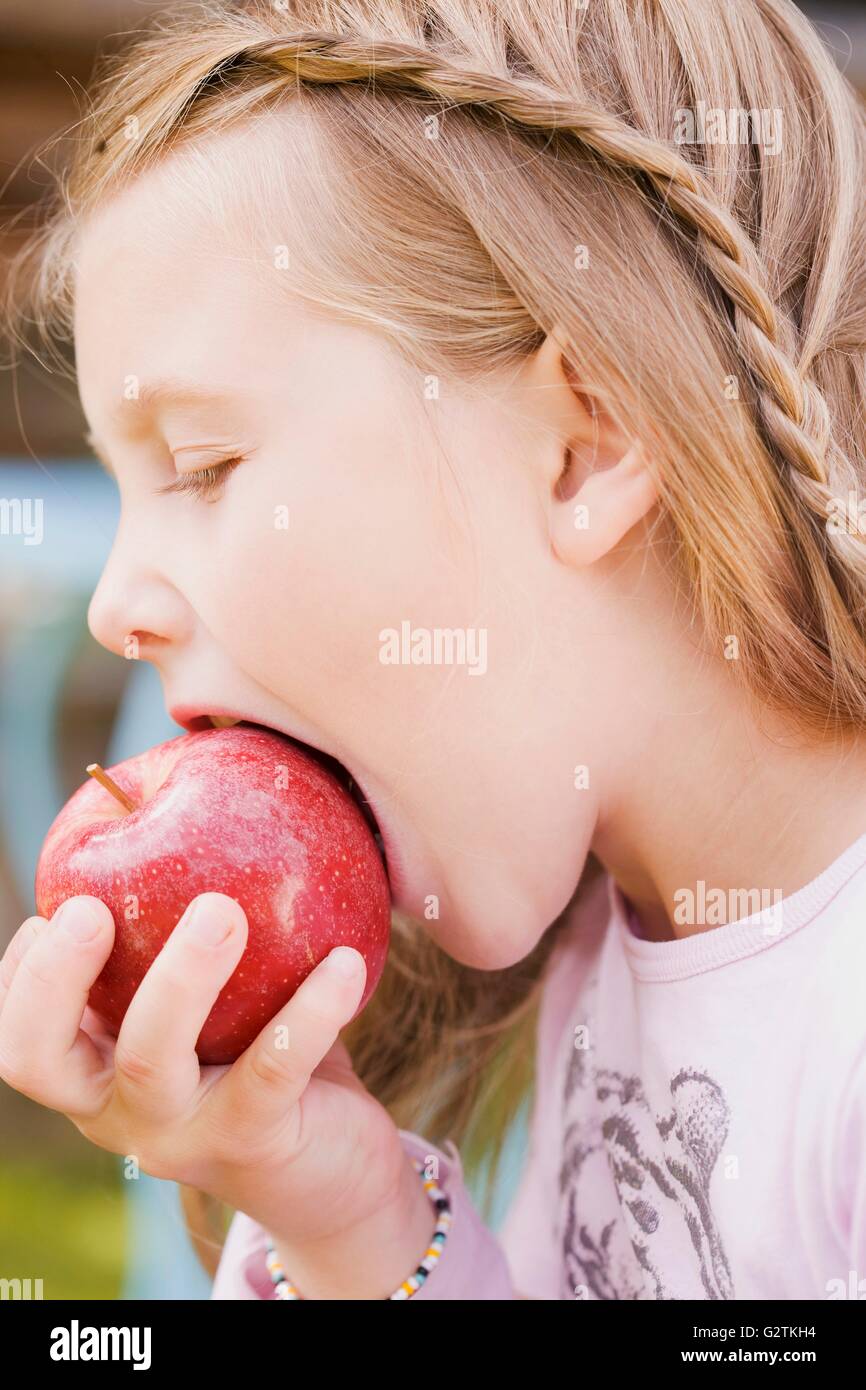 A girl biting into an apple Stock Photo - Alamy
