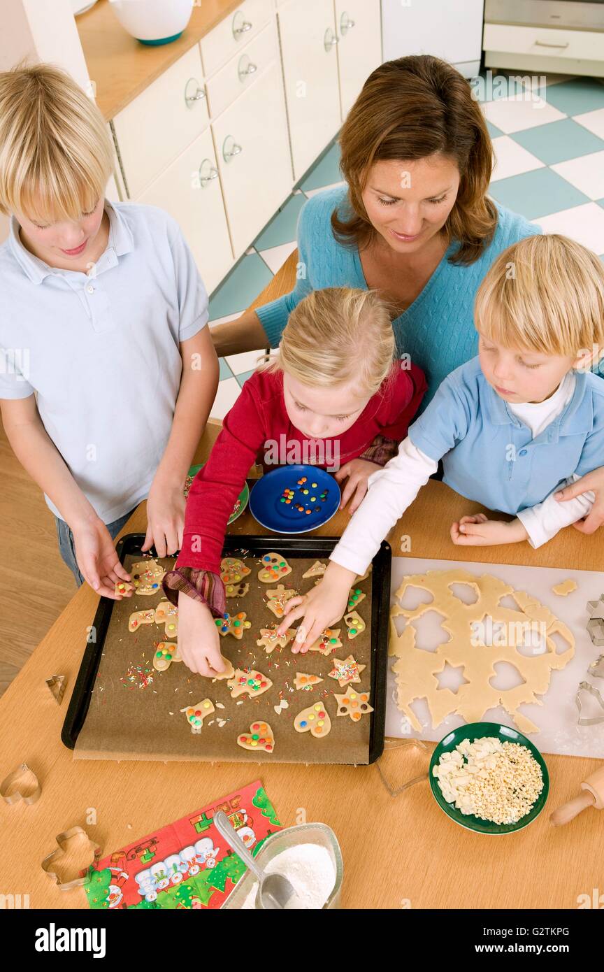 Mother and three children baking biscuits Stock Photo - Alamy