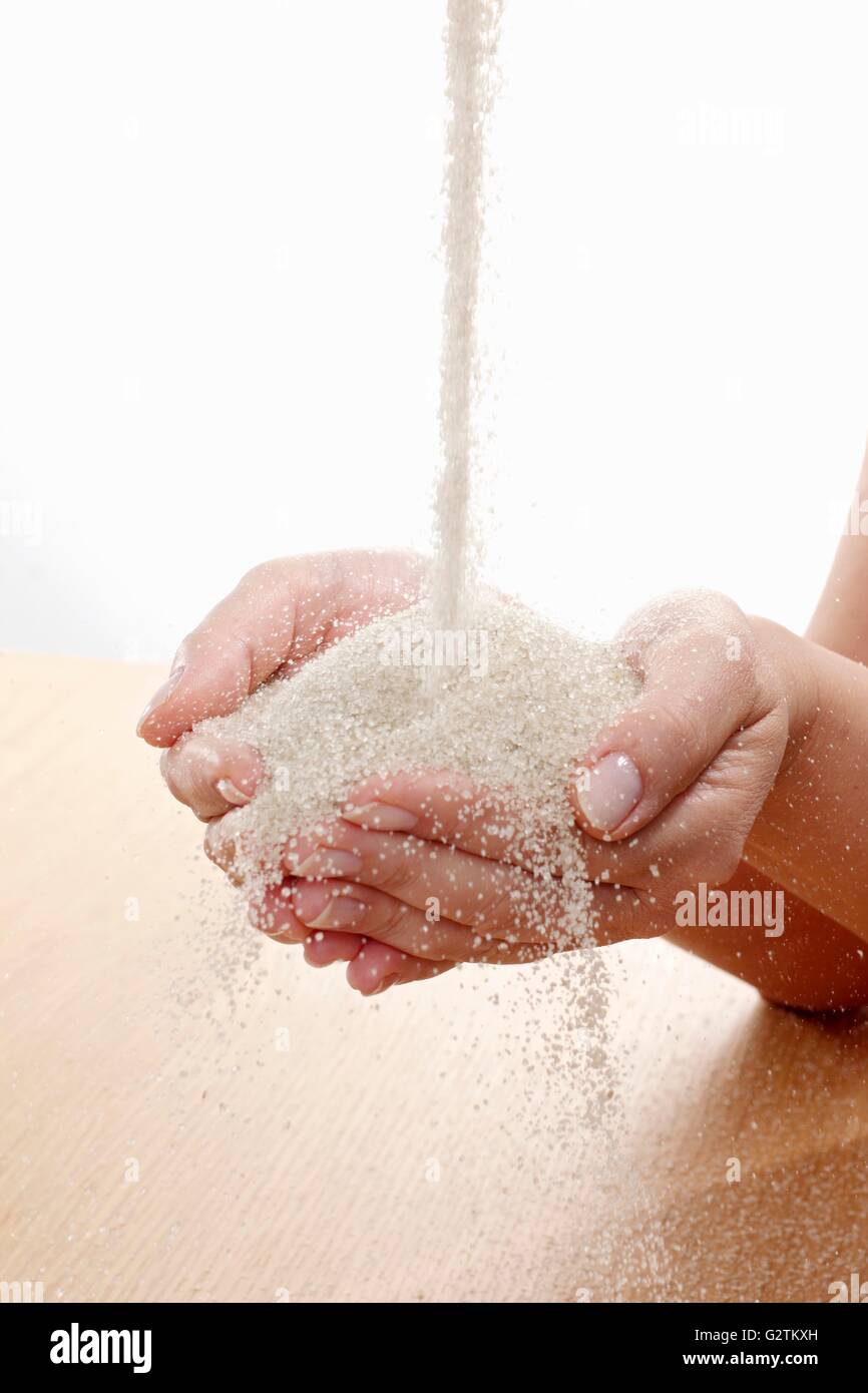 Raw sugar flowing into hands Stock Photo - Alamy