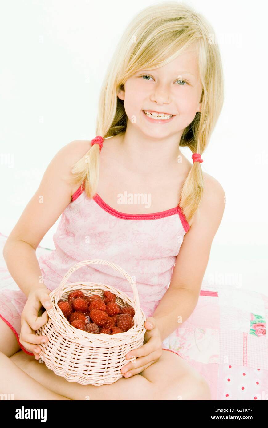 Blond girl holding small basket of fresh raspberries Stock Photo - Alamy