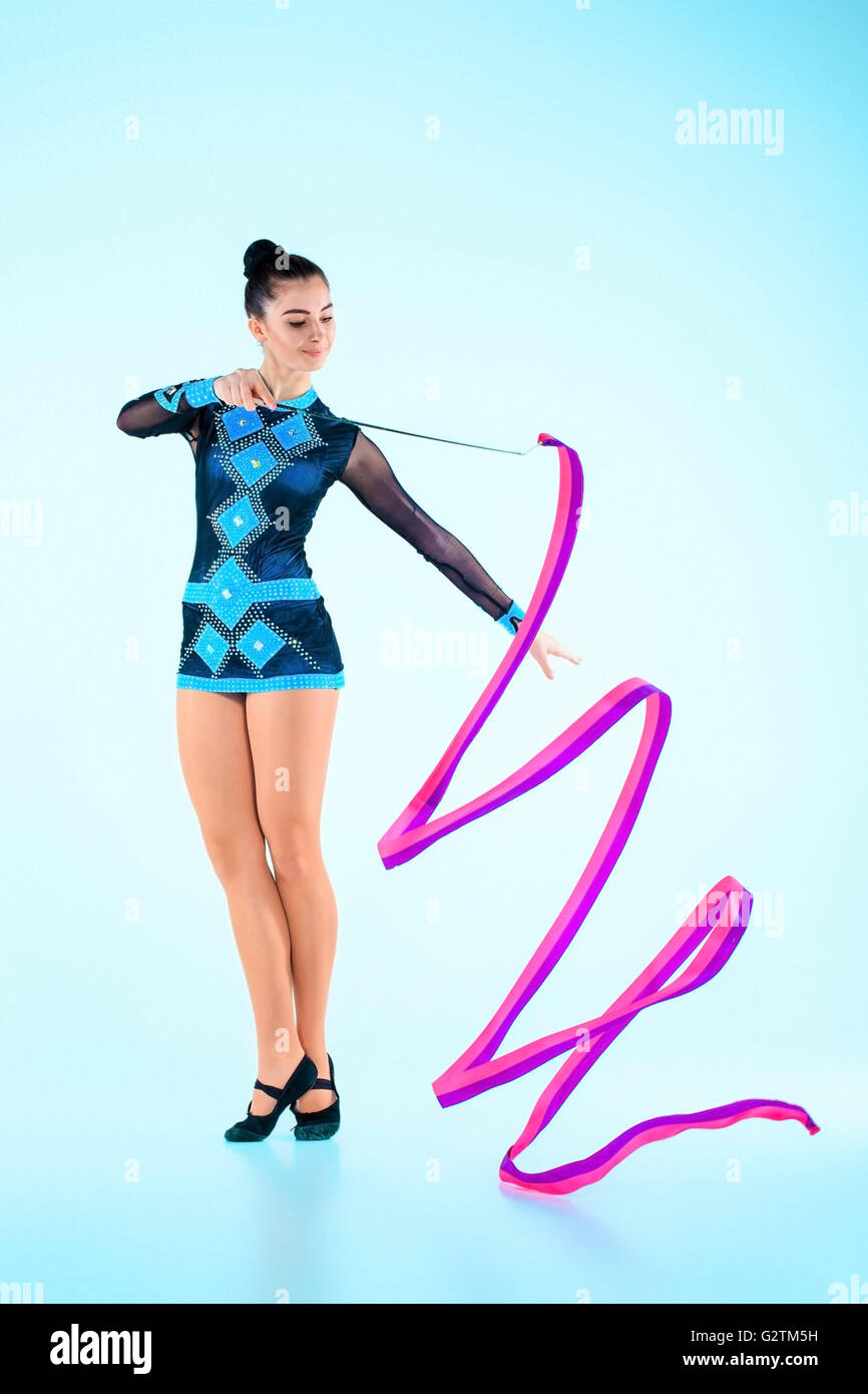 The girl doing gymnastics dance with colored ribbon on a gray ...