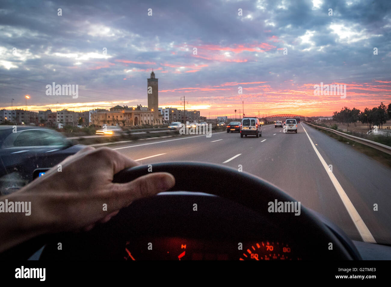 Driving in morocco at sunset with view of mosque Stock Photo - Alamy