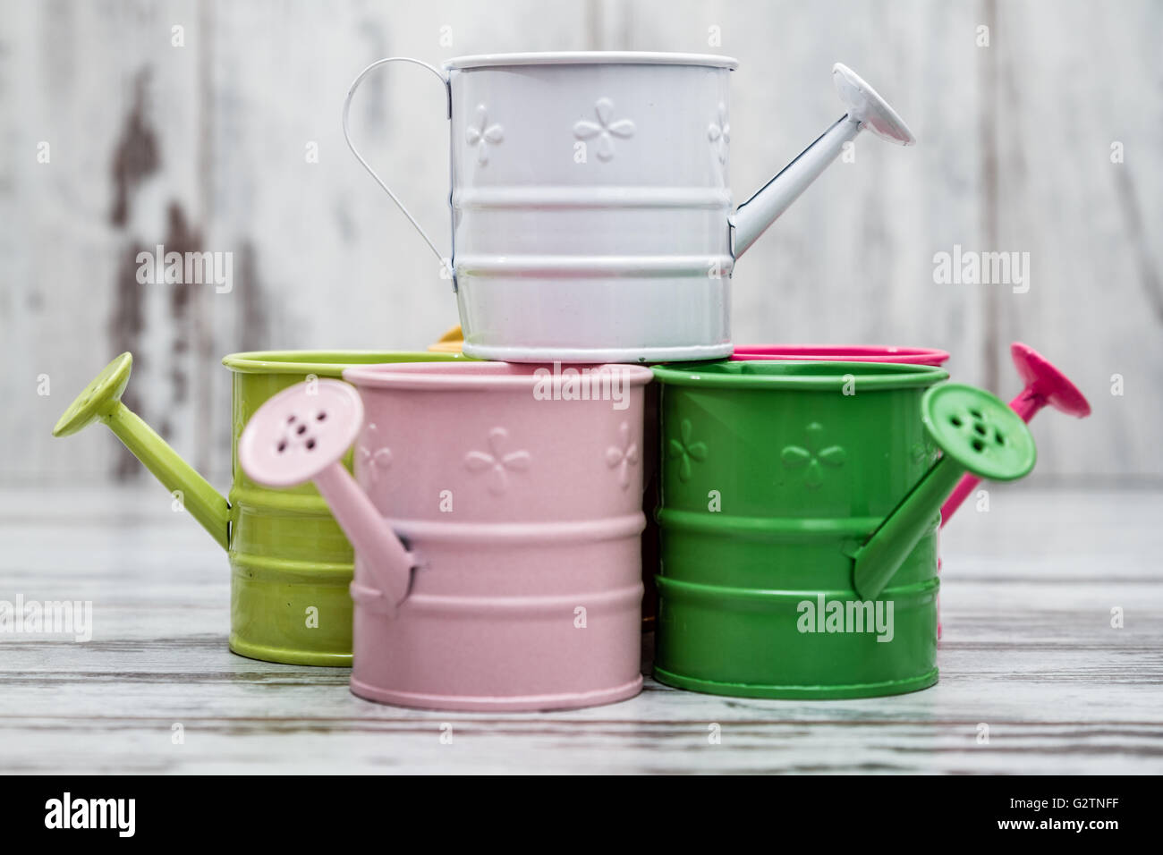Simple colorful metallic watering cans on white wooden background Stock ...