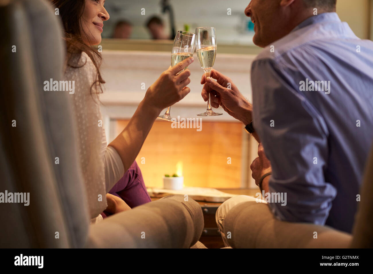 Couple Sitting By Fire Making Toast With Champagne Stock Photo - Alamy