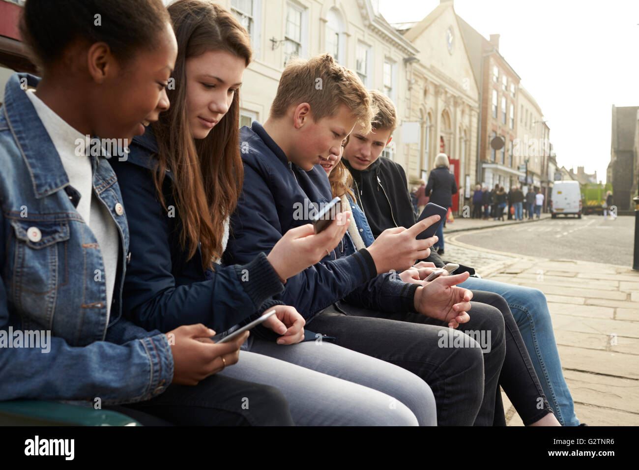 Teenage Friends Using Mobile Phones In Urban Setting Stock Photo - Alamy