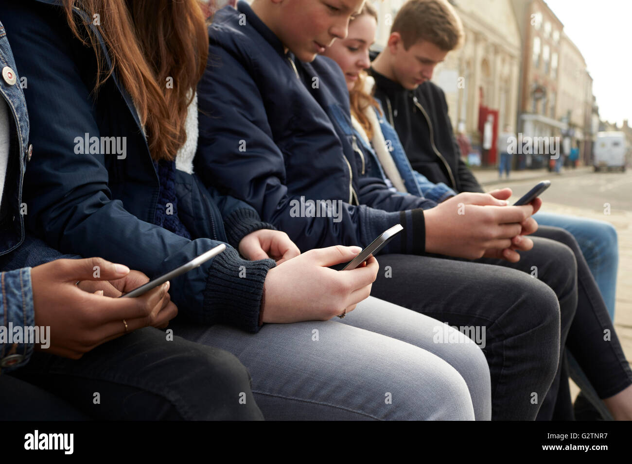 Teenage Friends Using Mobile Phones In Urban Setting Stock Photo - Alamy