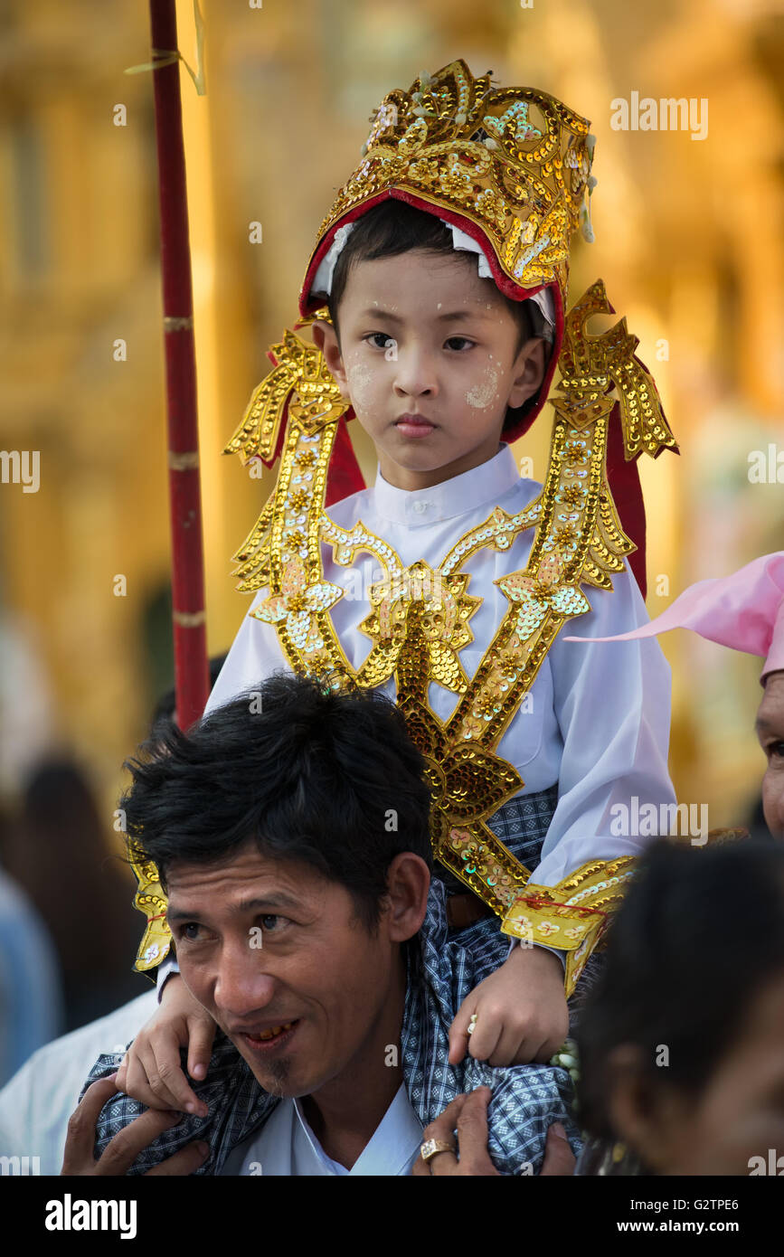 A boy on his father's shoulders during a shinbyu novitiation ceremony ...