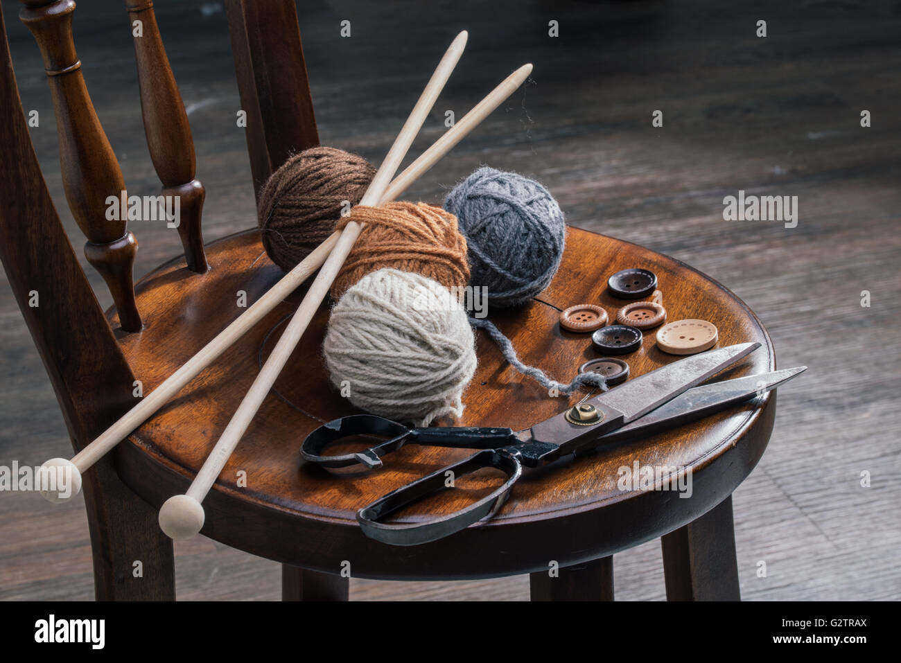 button, scissors and yarn ball on wooden chair, handmade Stock Photo ...